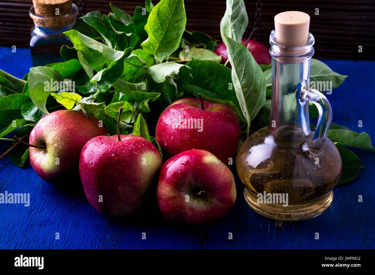 Apple cider vinegar. Three glass bottle on blue background. Red apples ...