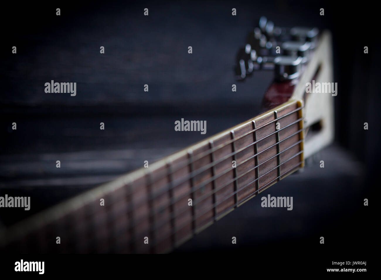 side view of acoustic guitar neck on black dark wooden background with ...