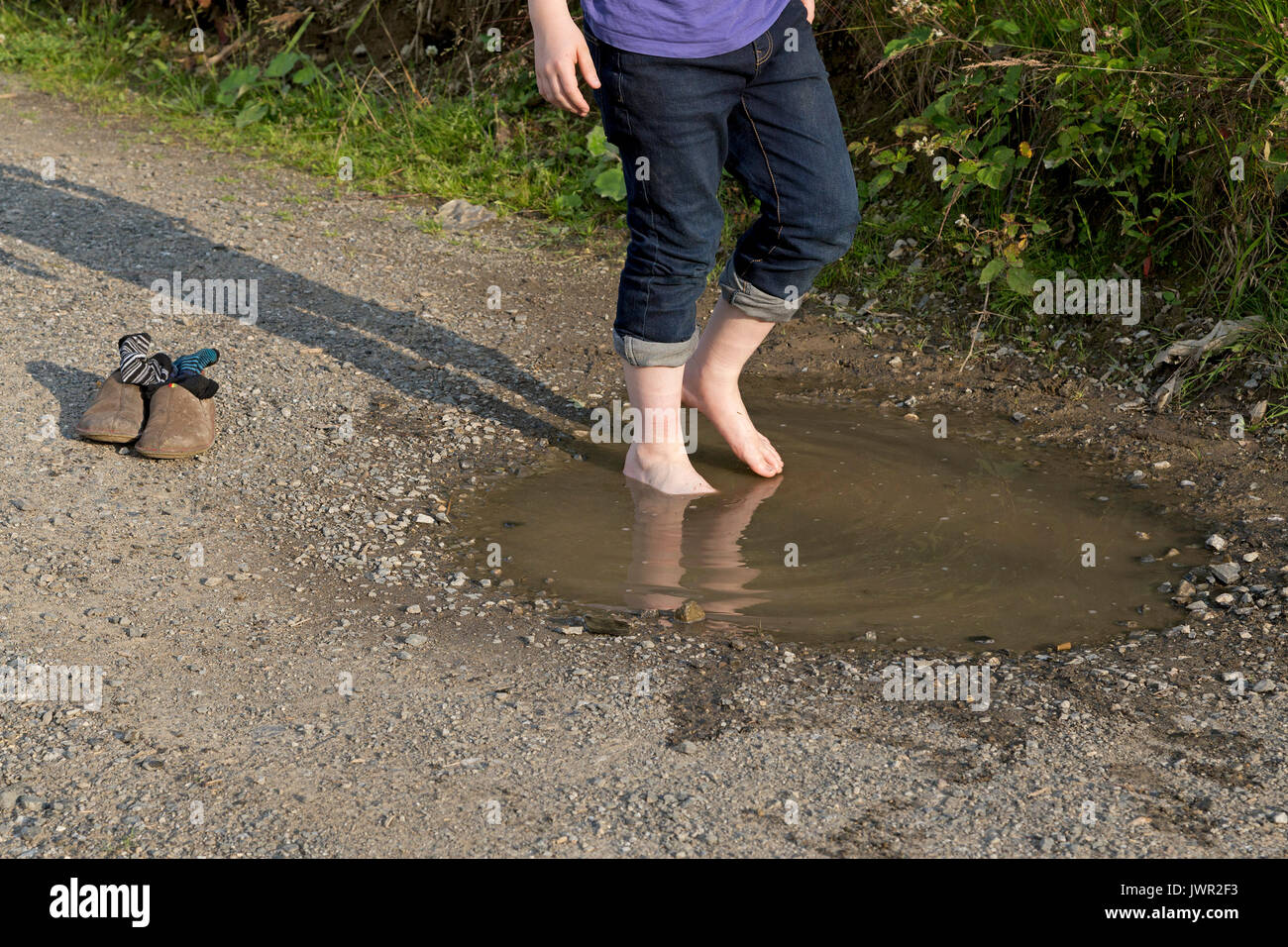 boy walking barefoot through puddle Stock Photo - Alamy