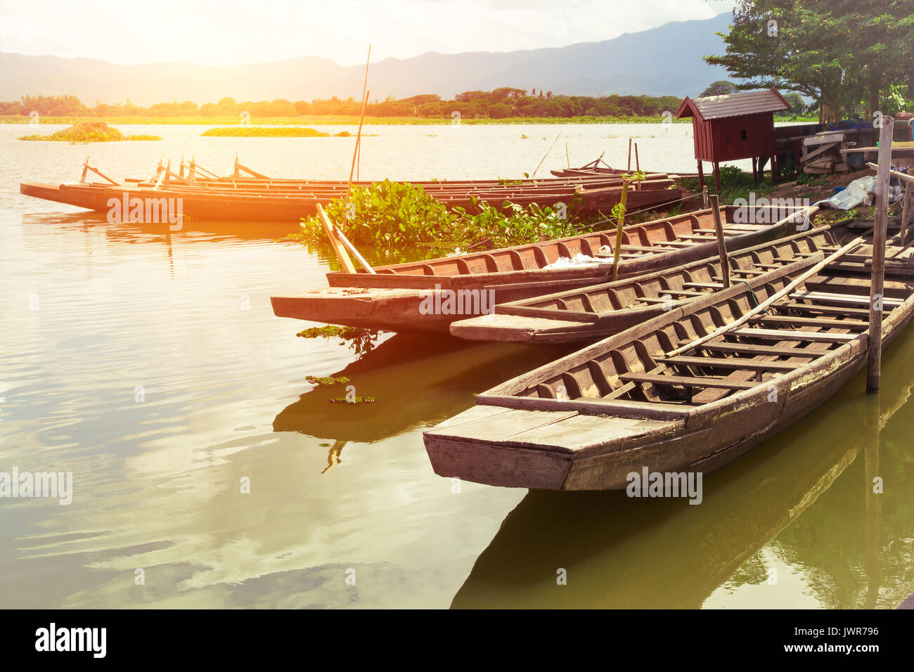 wooden boat float in reservoir with sunlight, mountain and clouds in ...