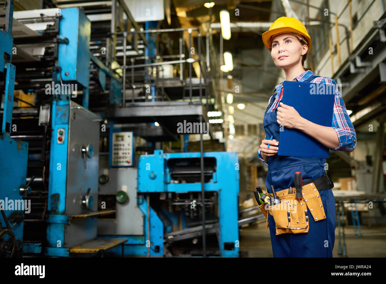 Portrait of young woman working in modern factory, walking between ...