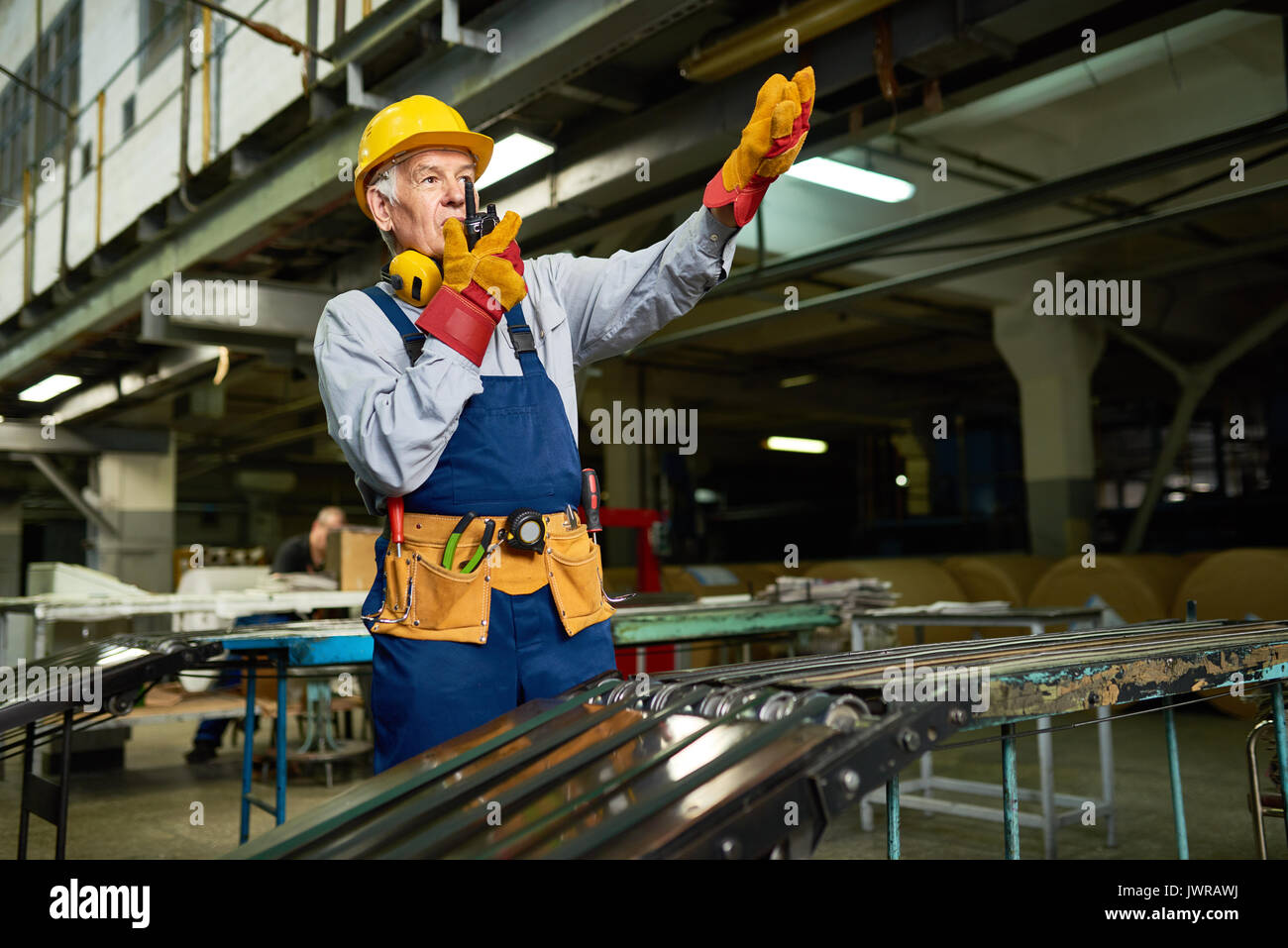 Portrait of senior factory worker giving instructions speaking by ...