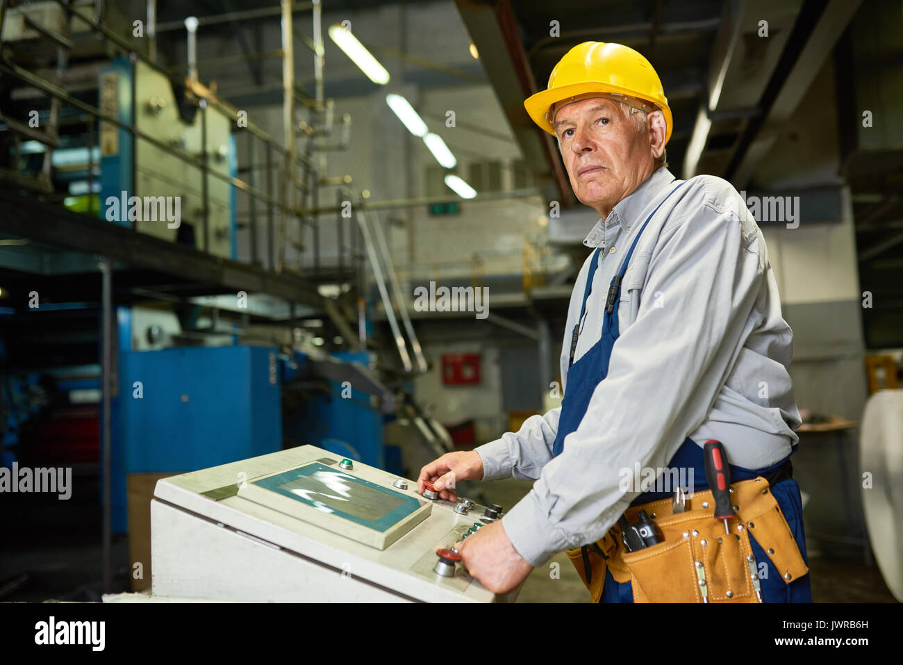 Portrait of senior man operating machine units in modern factory ...