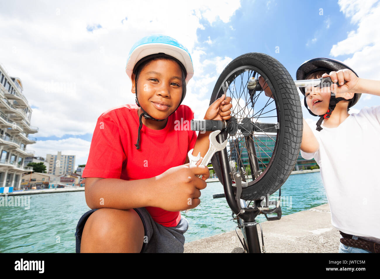 Happy African boy replacing bicycle tire, while his friend inflating ...