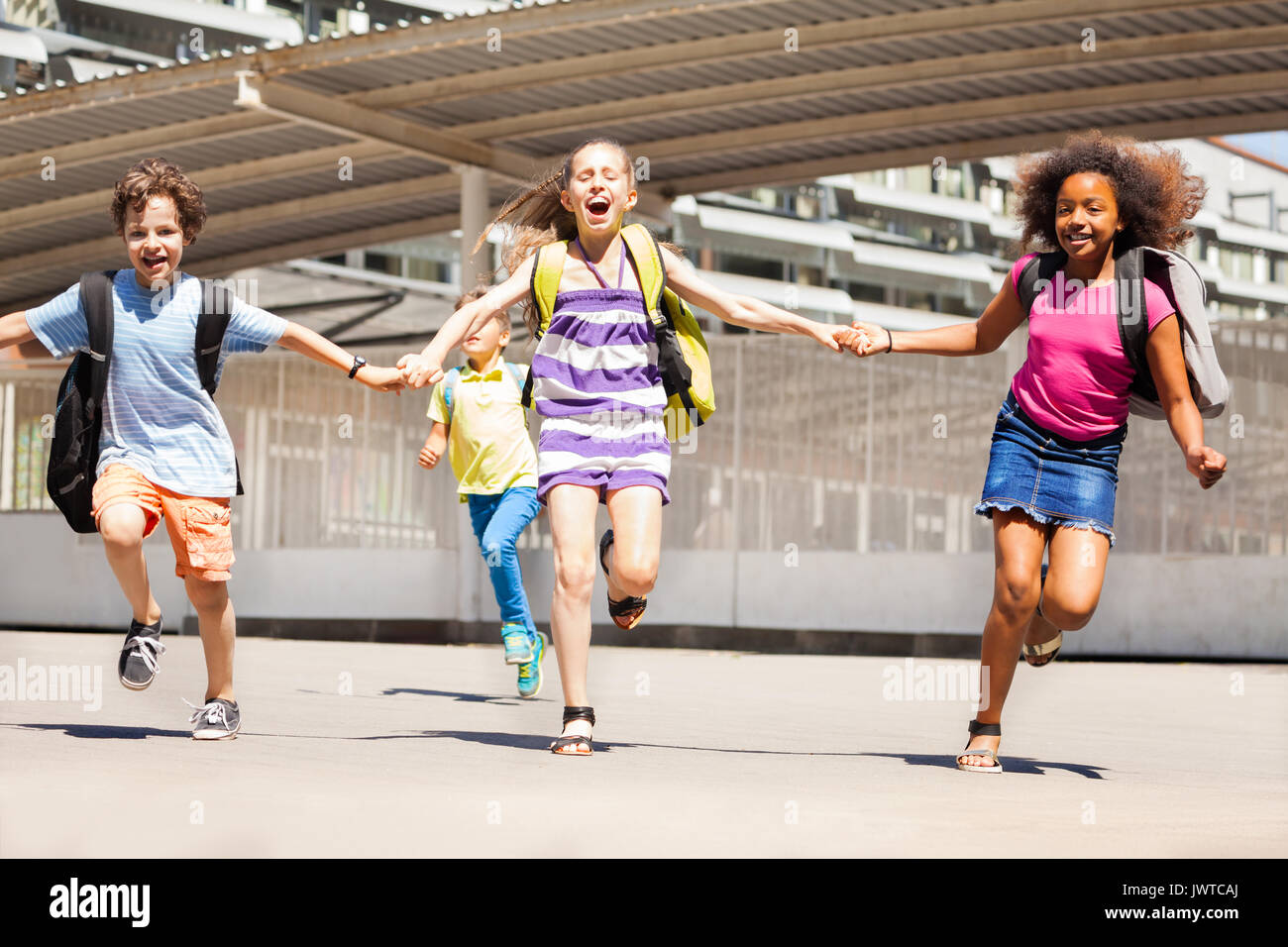Girls and boys running to school scramming happy looking to camera ...
