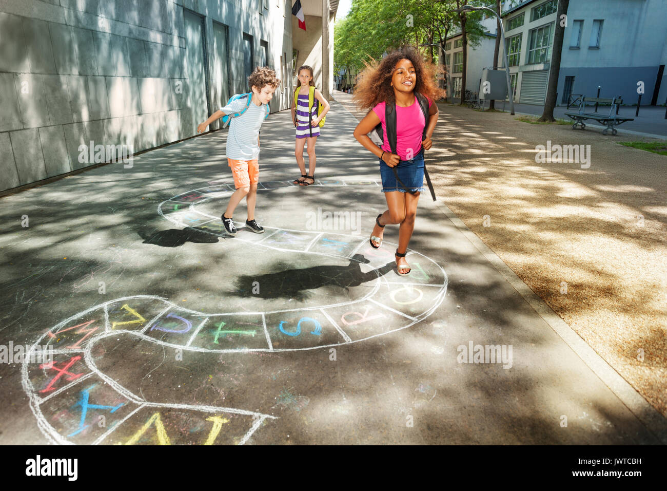 Group of kids jumping and paying hopscotch game outside near the school ...