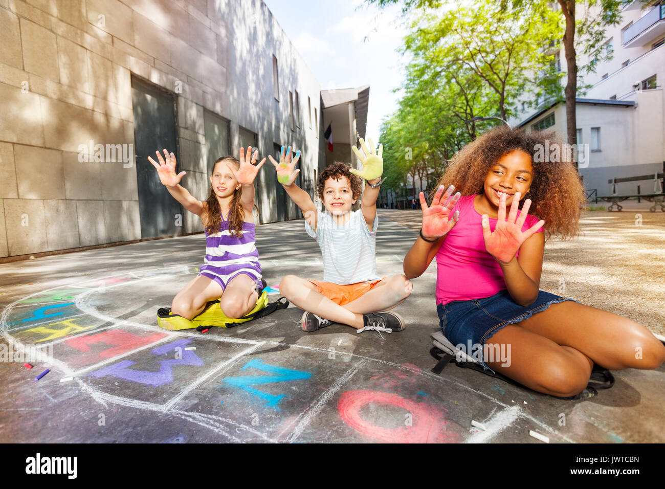 Group of kids show color palms in chalk looking at camera Stock Photo ...