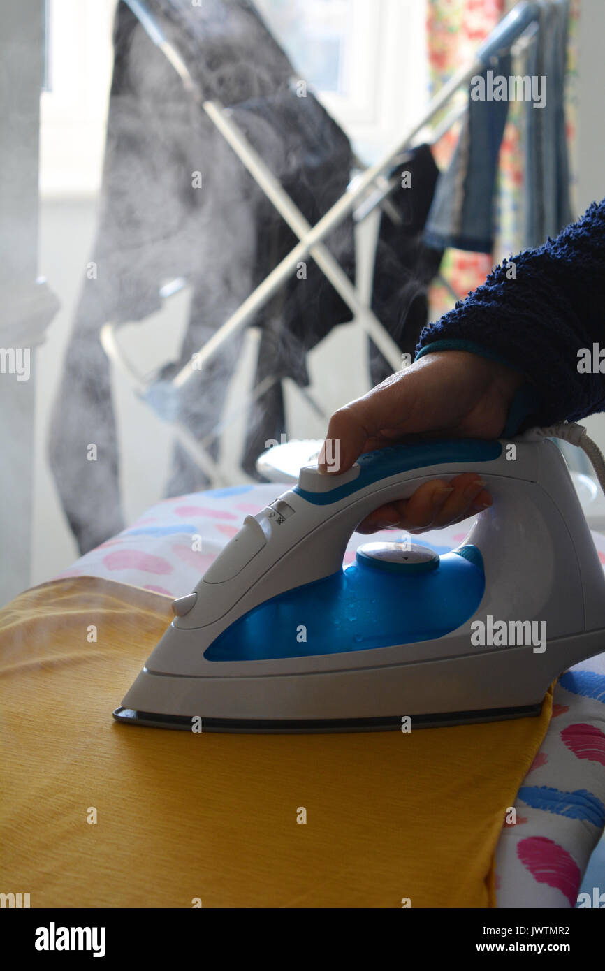 Housework. Woman doing the ironing, close-up of iron and ironing board ...