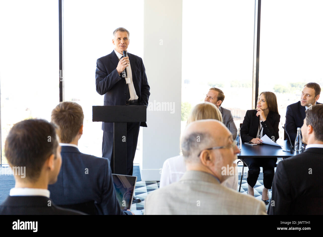 Business speaker with microphone in front of audience, conference ...