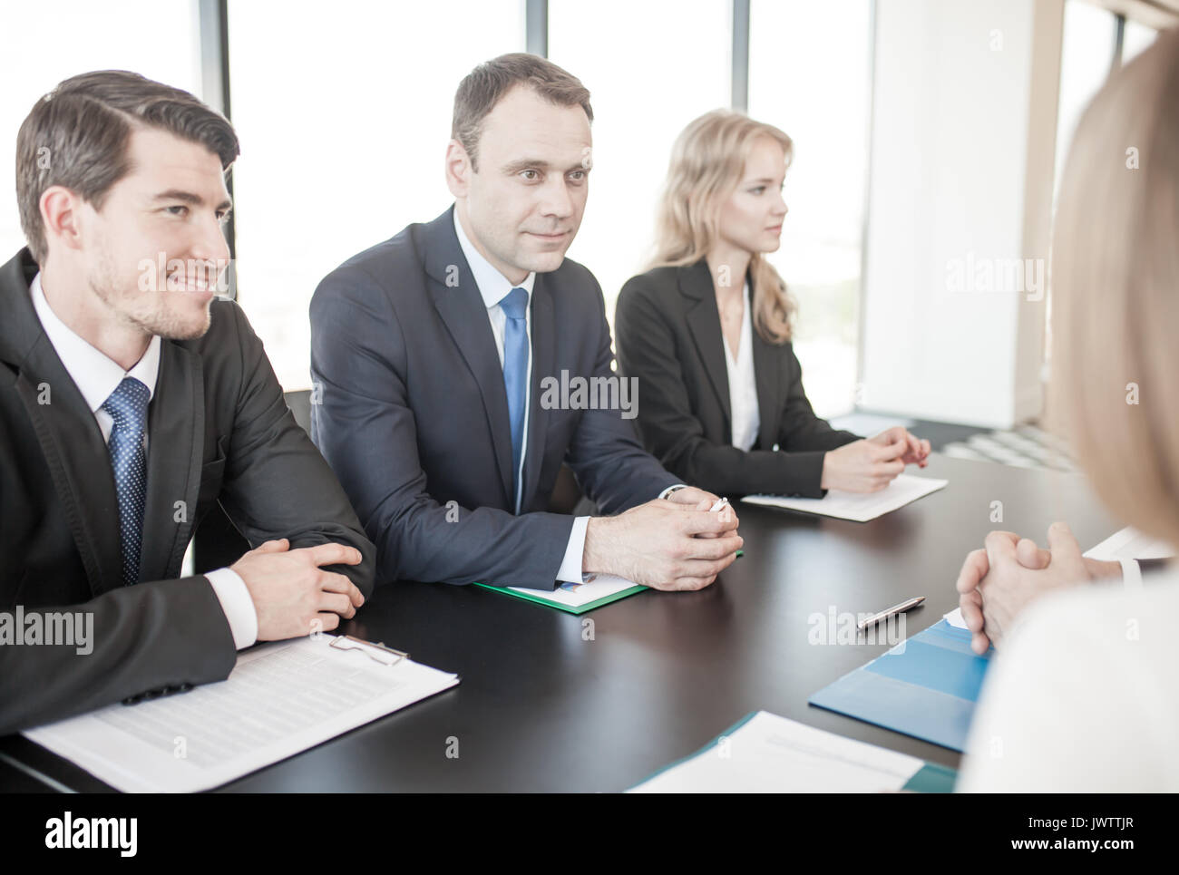 Business people sitting around meeting table, talking and working with ...
