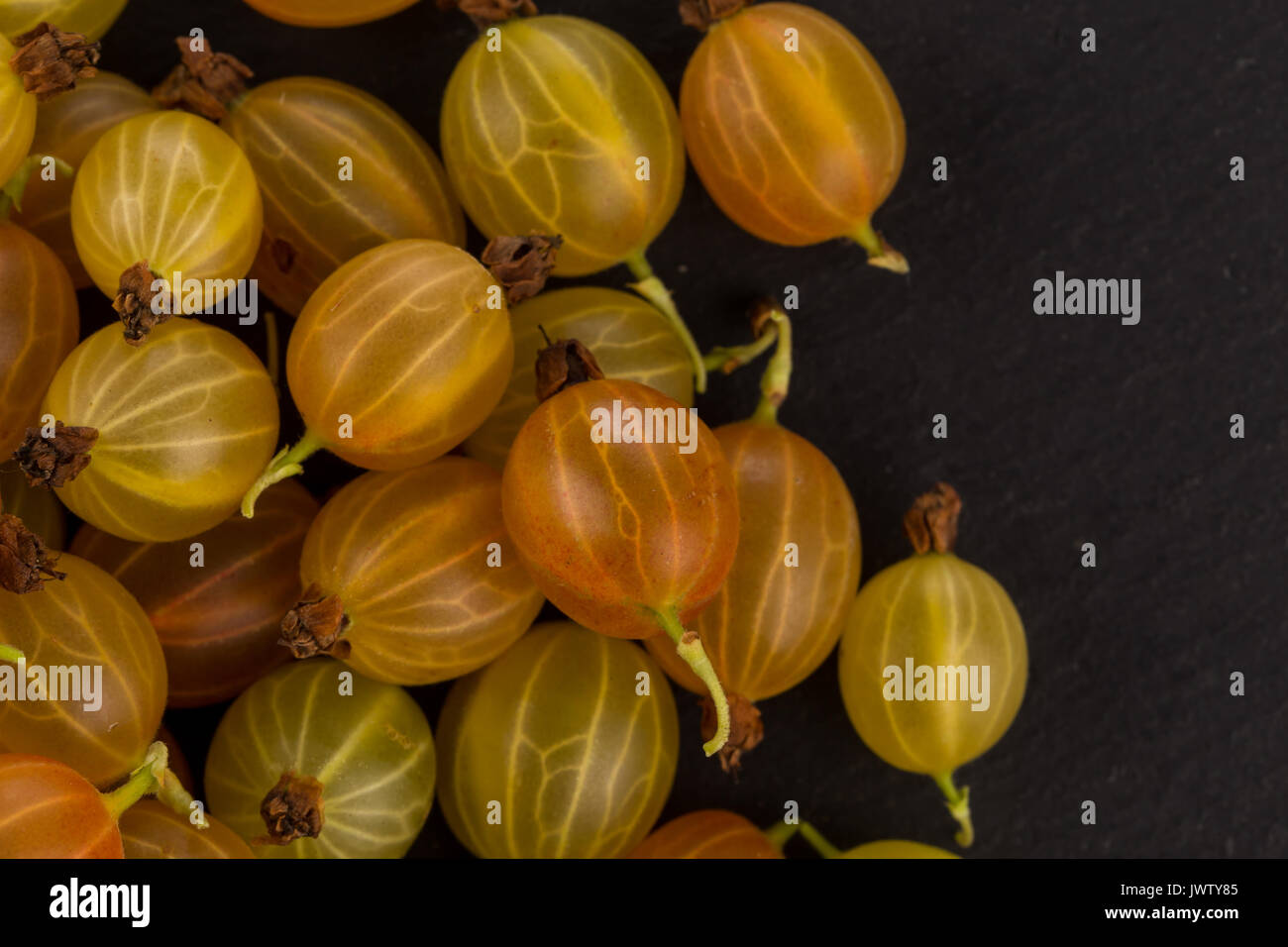 Fresh juicy gooseberry on stone dark background Stock Photo - Alamy