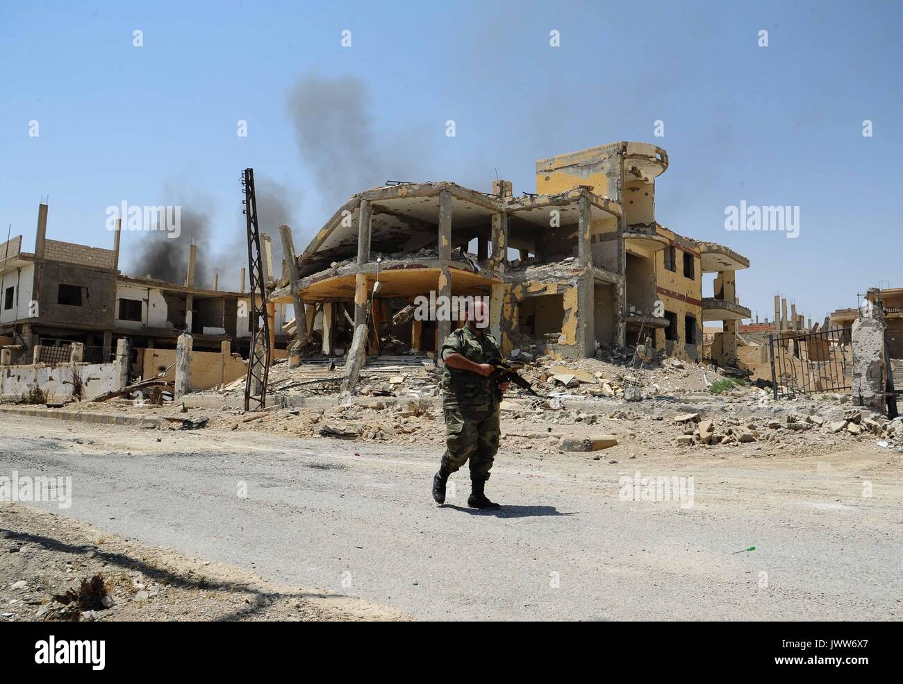 Al-Sukhnah, Syria. 13th Aug, 2017. A Syrian soldier walks as smoke ...