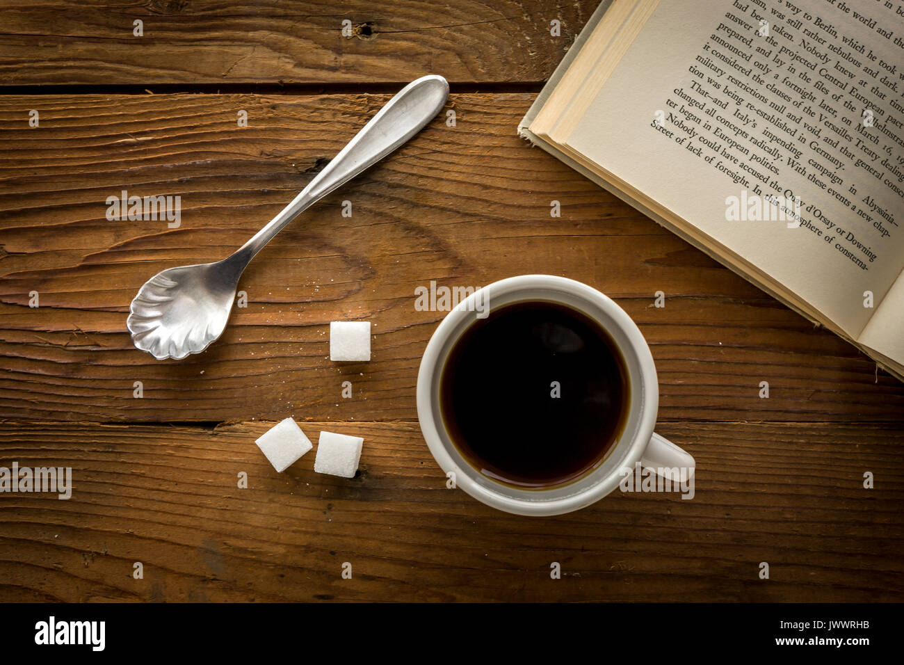 An overview of a cup of coffee, sugar cubes, a spoon, and a book Stock ...