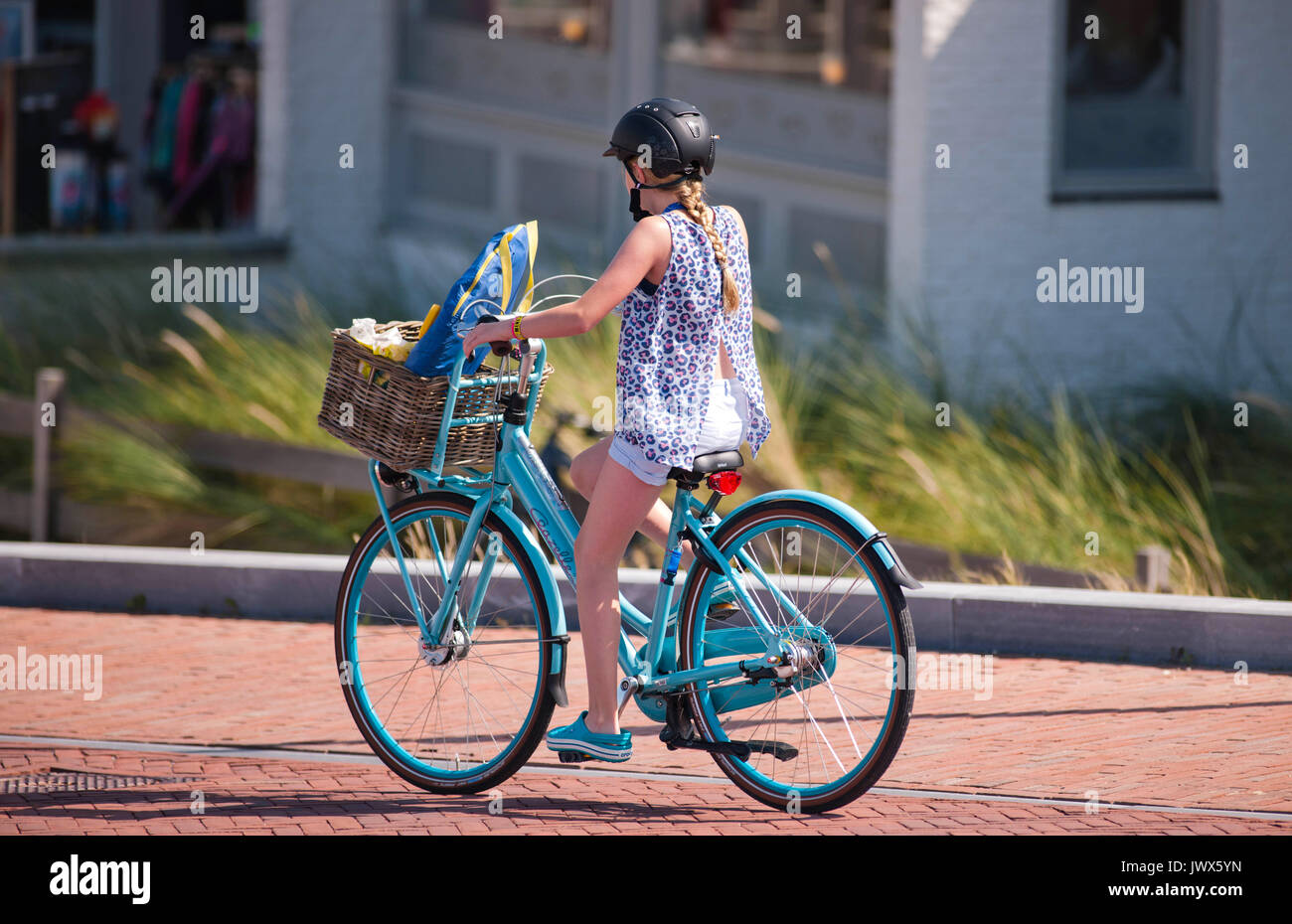 Young girl riding her bike and wearing a helmet on her head for safety ...