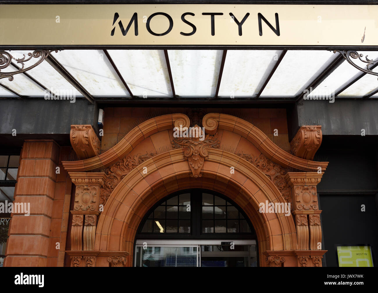 Glazed canopy above terracotta arched doorway and open pediment, at the ...