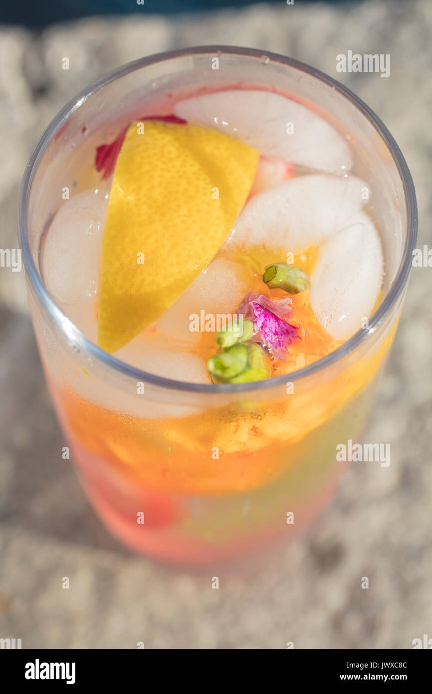 Glass of cold water infused with fruit, mint and edible flowers and ice ...