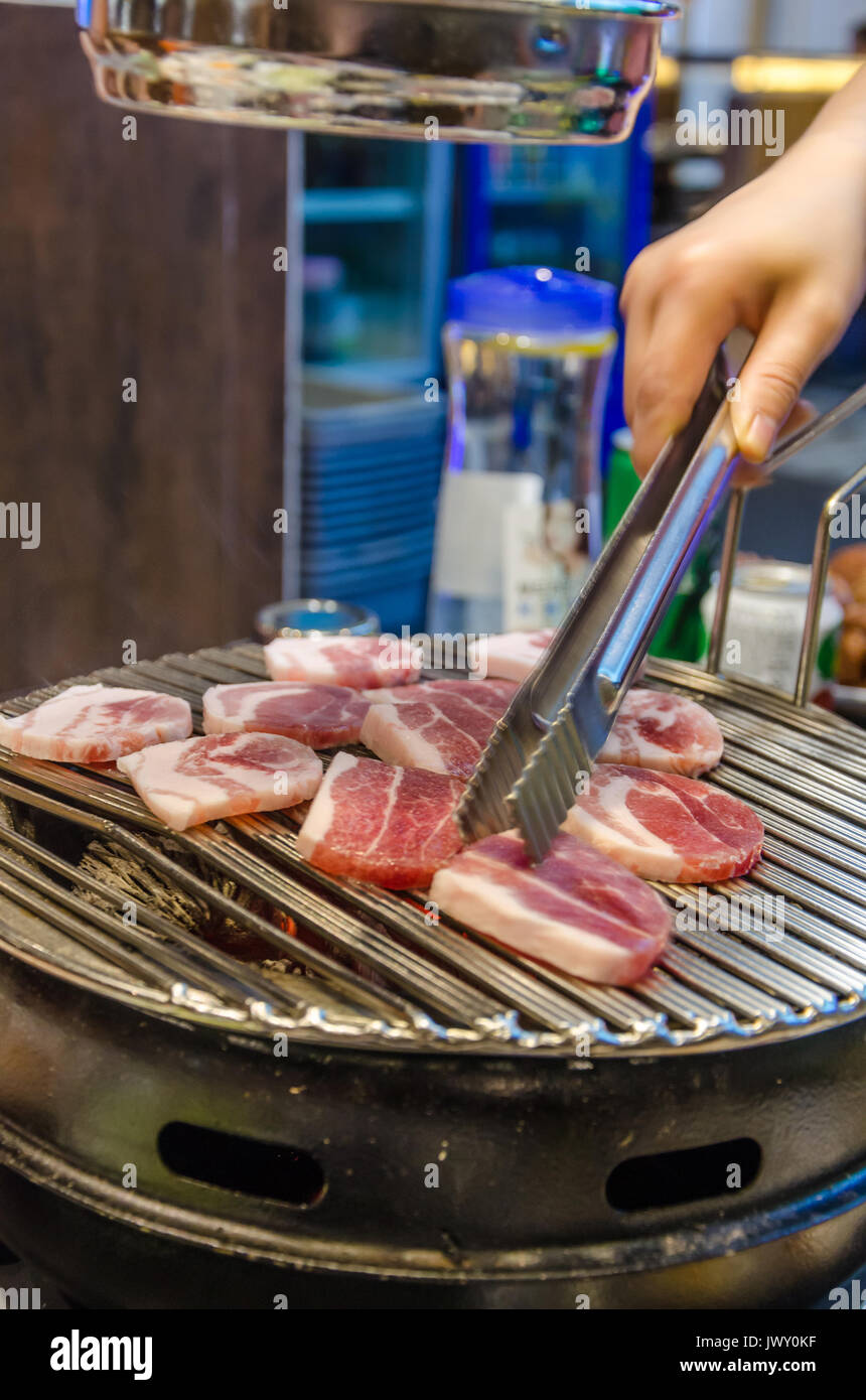 Meat cooking on a Korean Barbeque in a Koream restaurant. The meal is ...