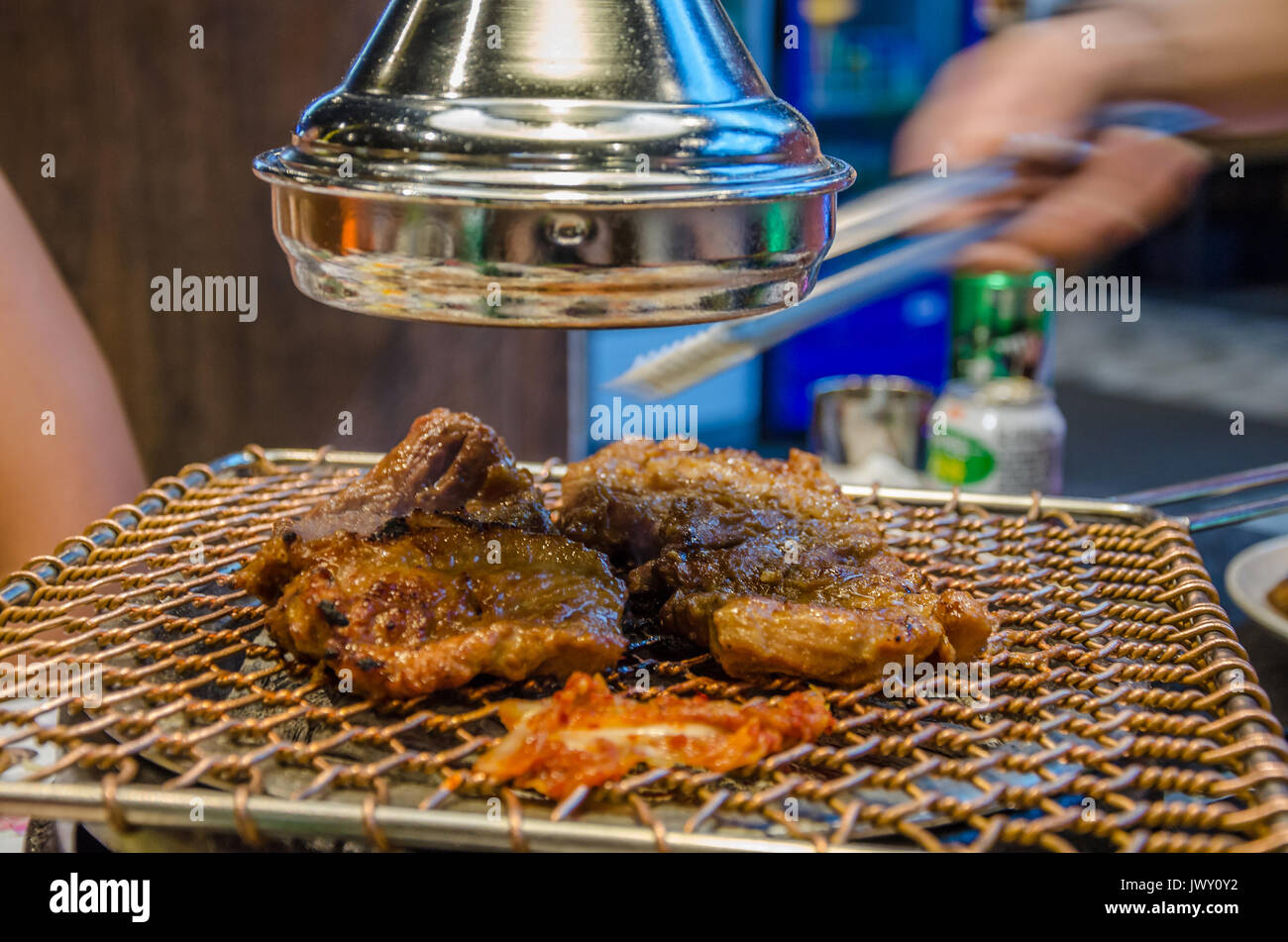 Meat cooking on a Korean Barbeque in a Koream restaurant. The meal is ...