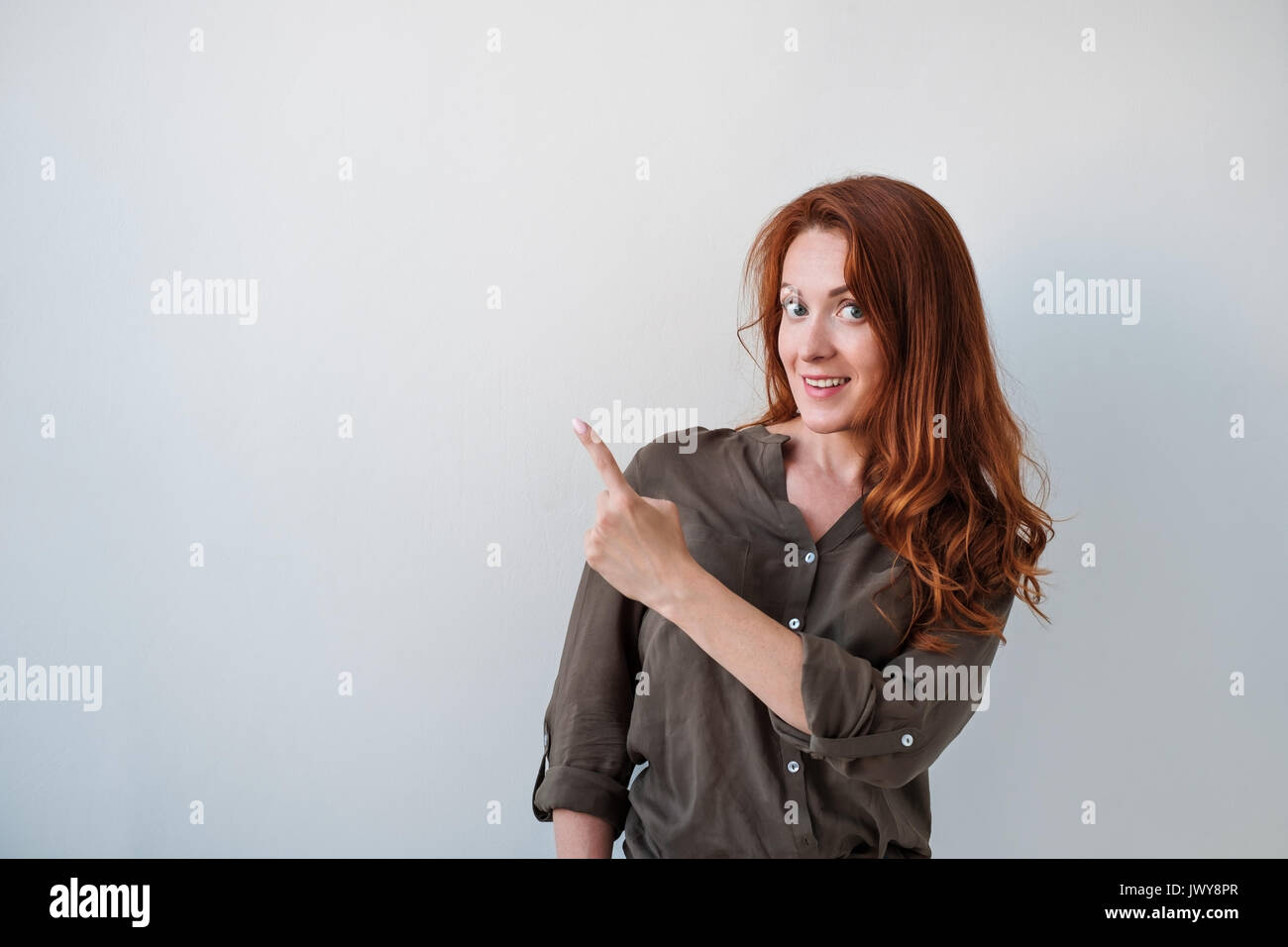 Pretty woman with red hair gesturing with fingers and showing away ...