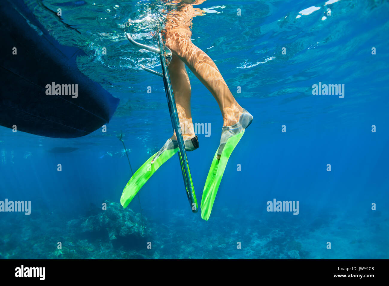 Child in snorkelling fins stand on divers boat ladder for diving ...