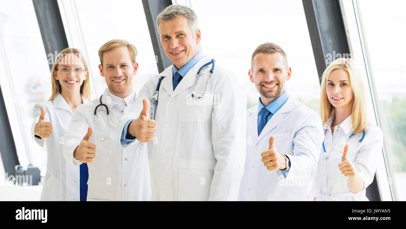 Successful team of medical doctors are looking at camera and showing ...