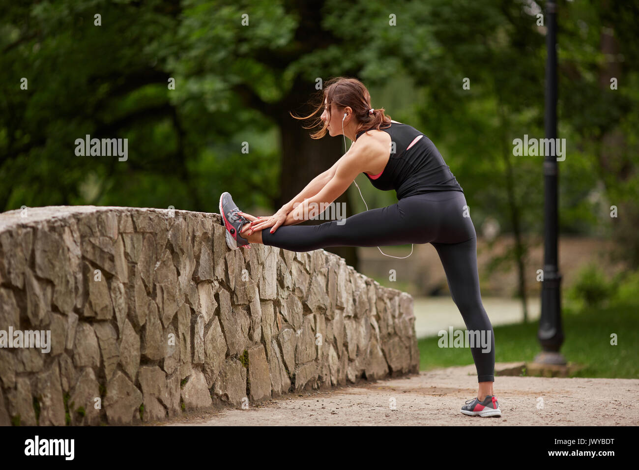Sportswoman stretching legs on fence Stock Photo - Alamy