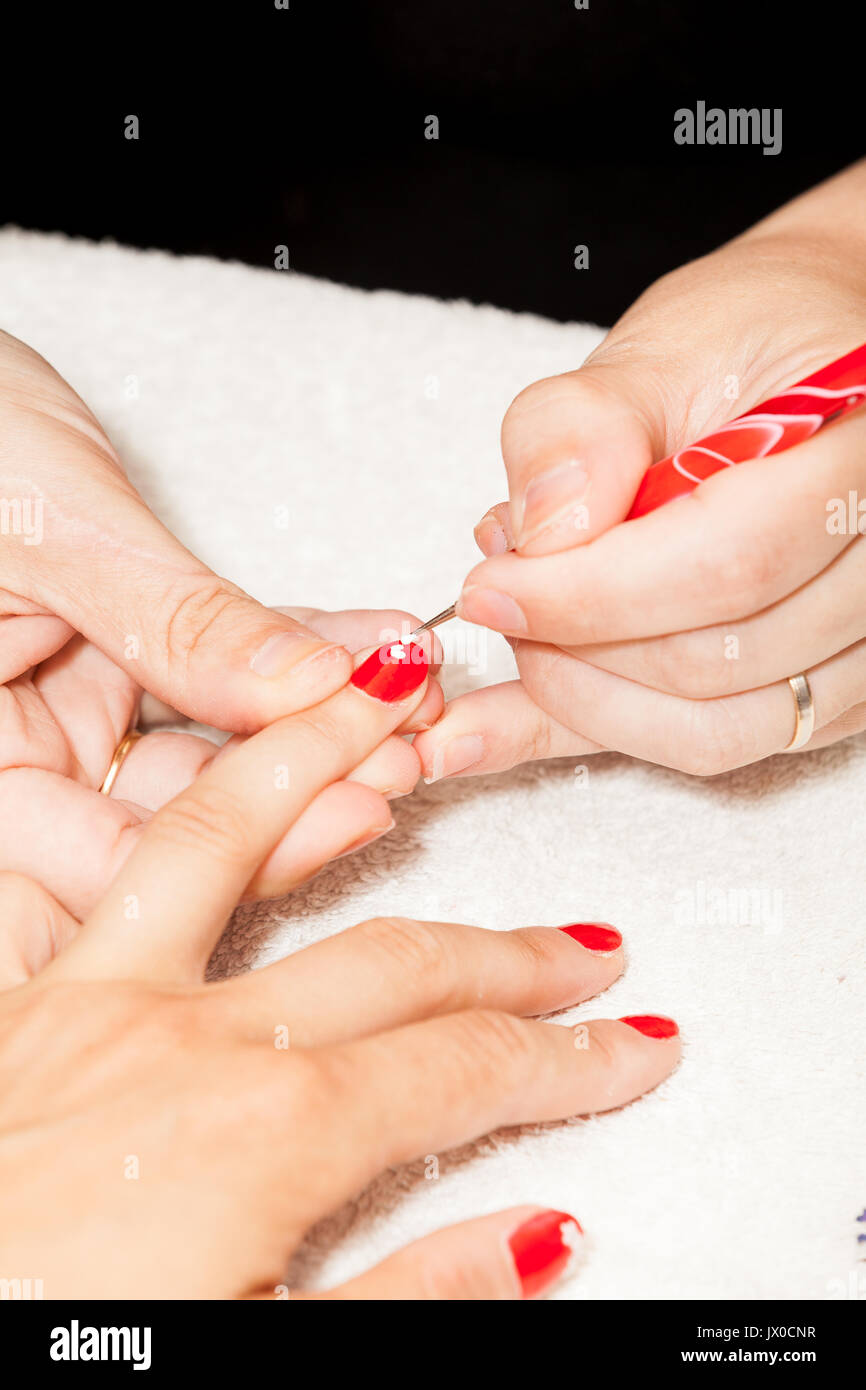 The esthetician decorates with flowers the nails of the hands of the ...