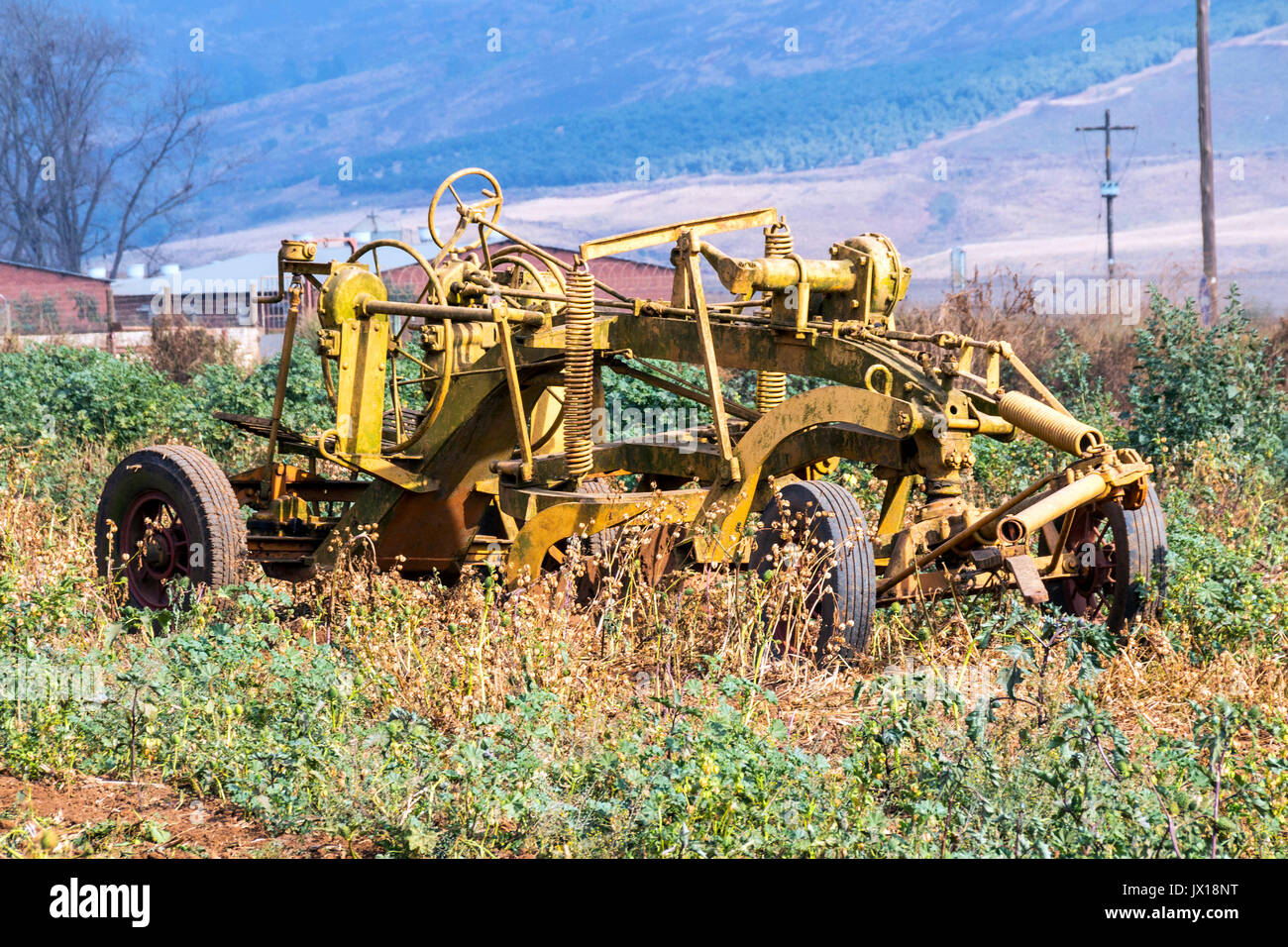 Vintage yellow farm implement against rural farm landscape in South ...
