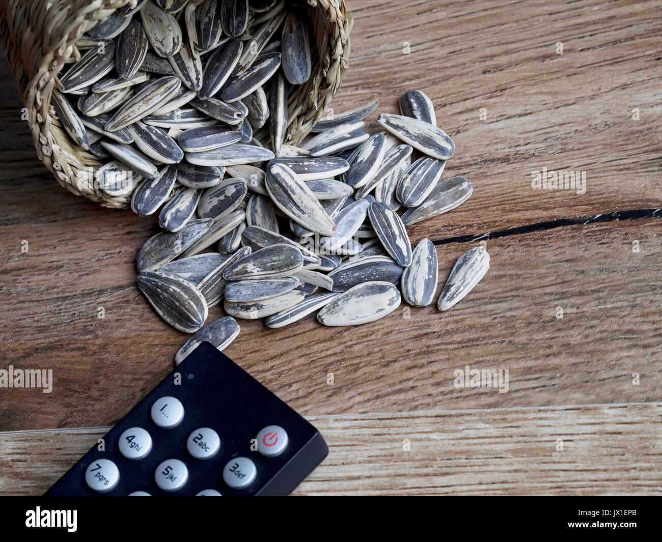Sunflower seeds in wicker basket and remote control tv Stock Photo - Alamy