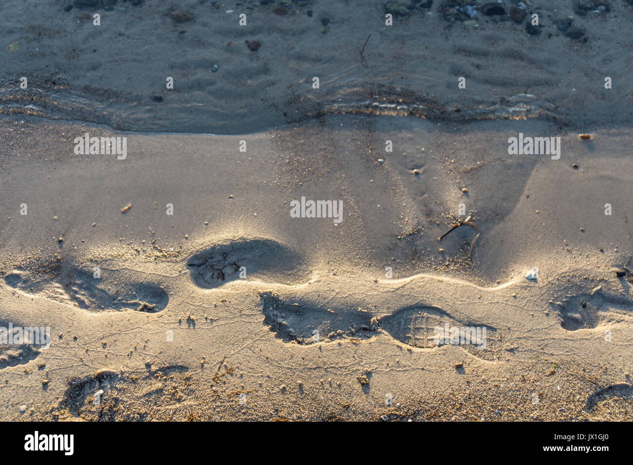 Beach side with wet footsteps after the beach guests Stock Photo - Alamy