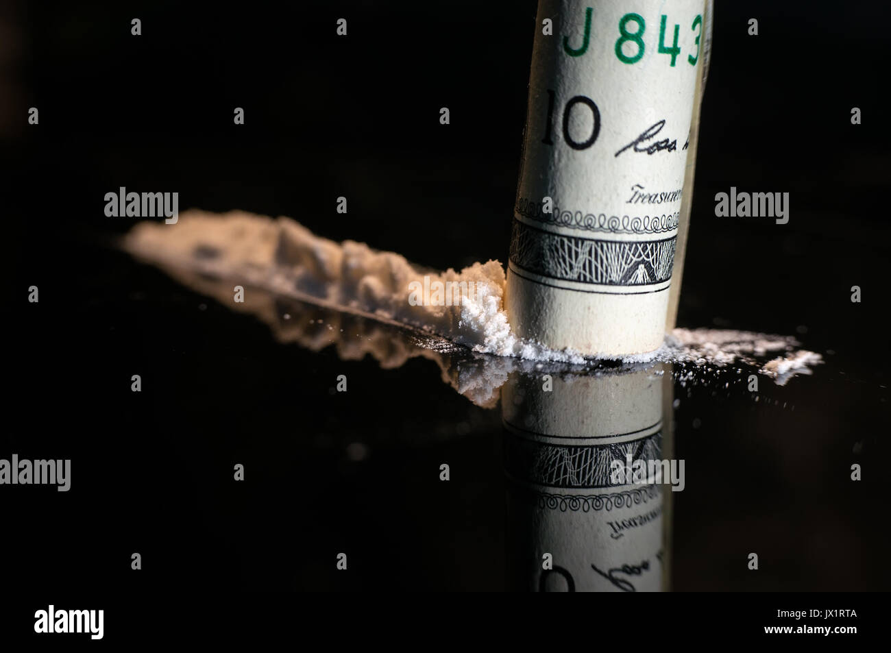 Snorting a line of cocaine. There are three lines on a glass table ...