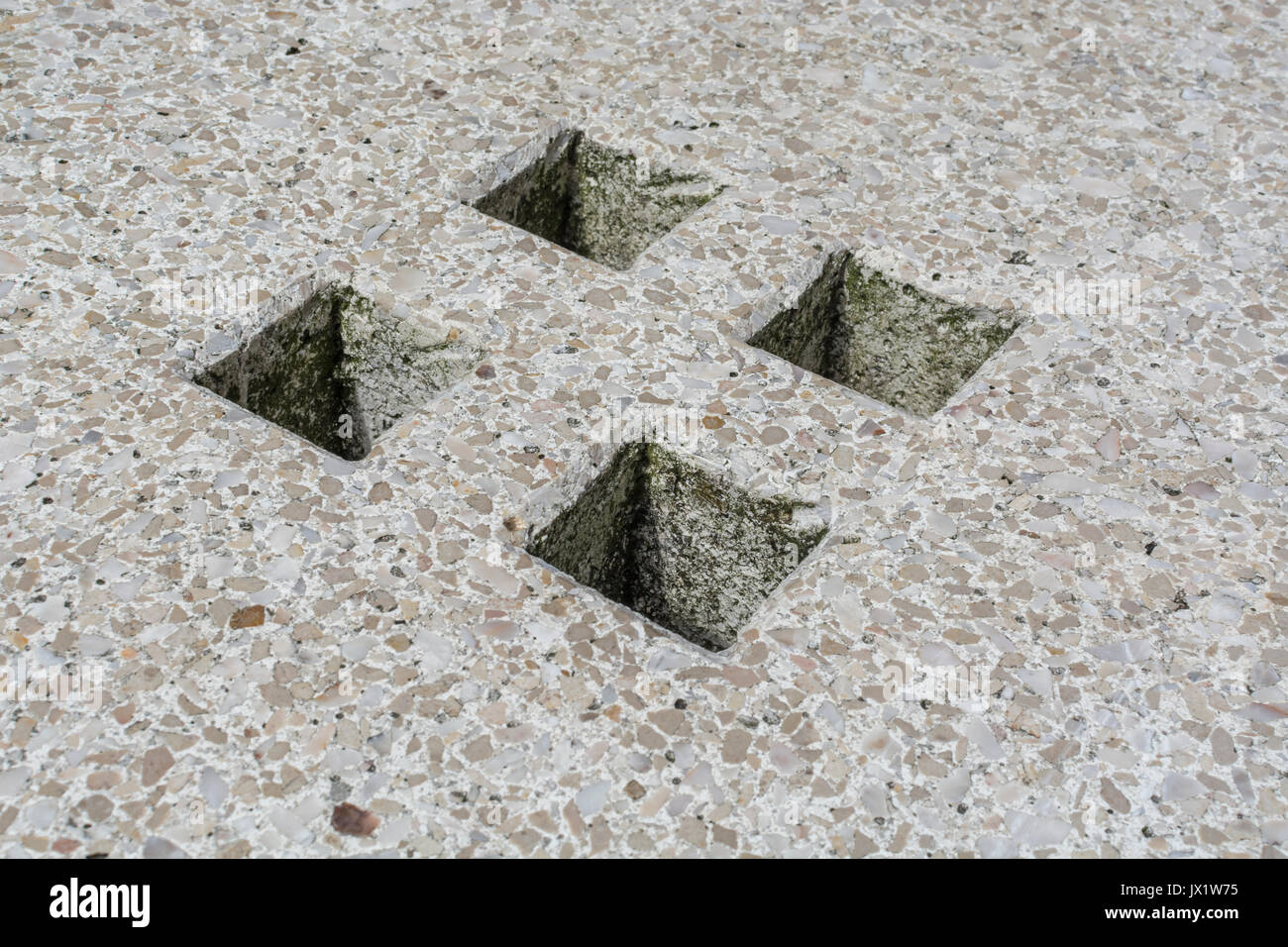 Four square holes in a concrete public bench seating Stock Photo - Alamy
