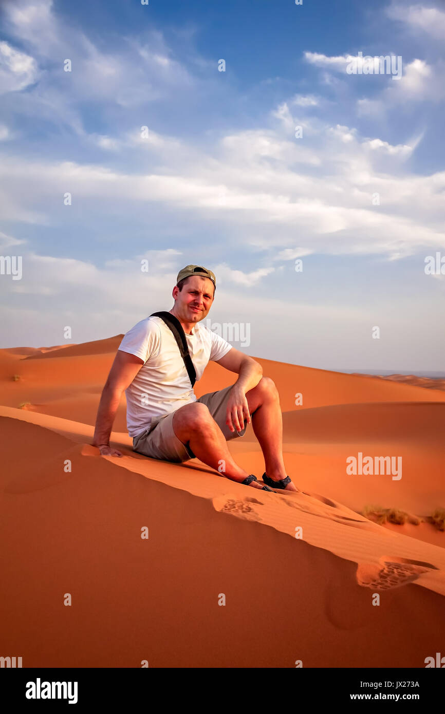 Tourist resting on top of the stunning sand dunes of Sahara desert in ...