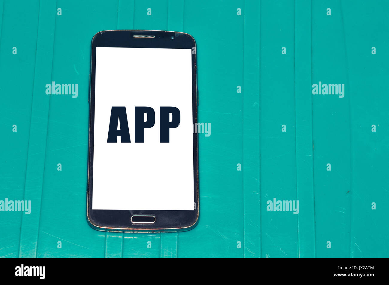 app written on smartphone screen on blue background, technology concept ...