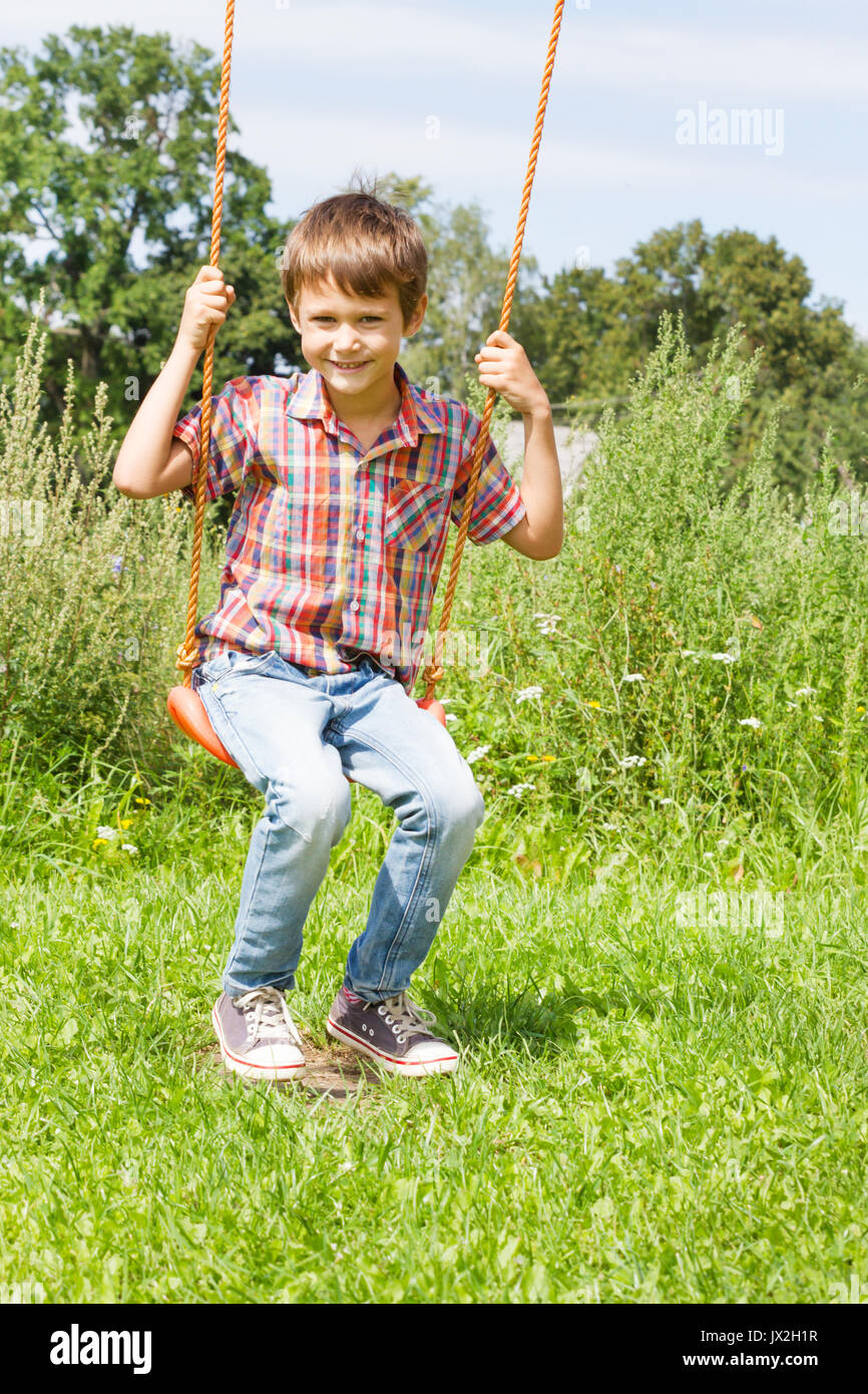 Happy little kid swinging on swing outdoor Stock Photo - Alamy