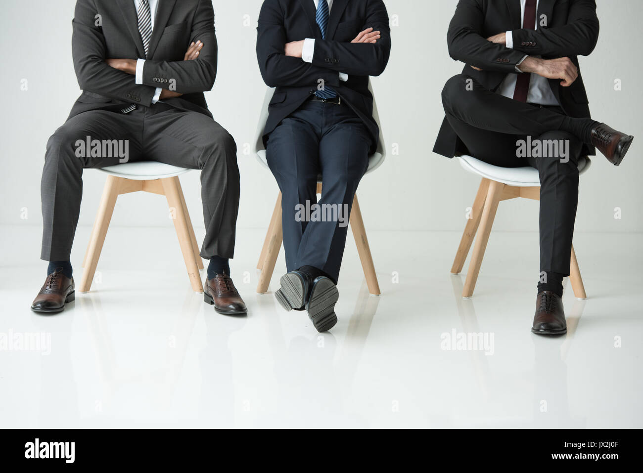 low section of businessmen sitting on chairs isolated on white ...