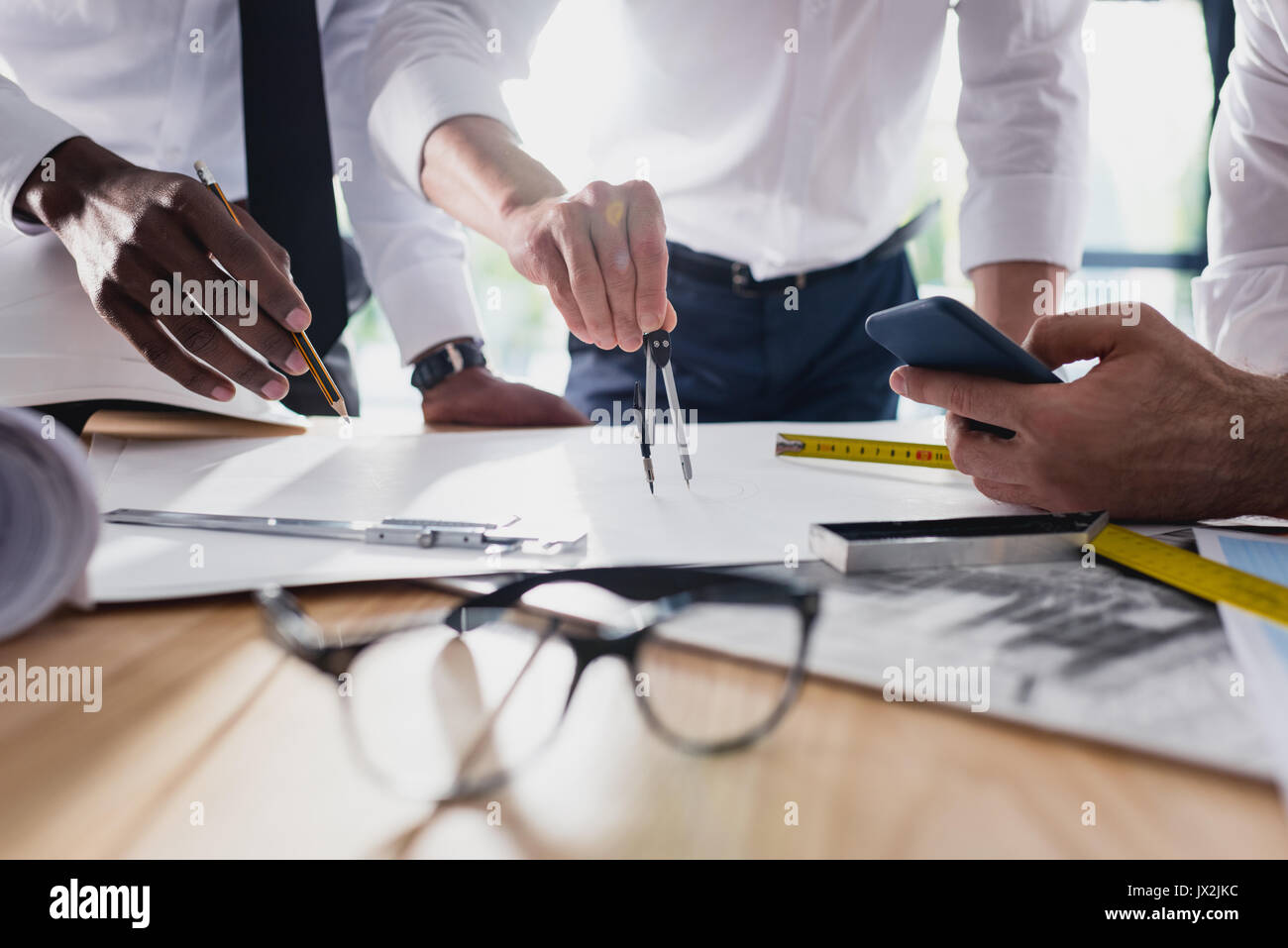 partial view of team of architects working on plan together in modern ...