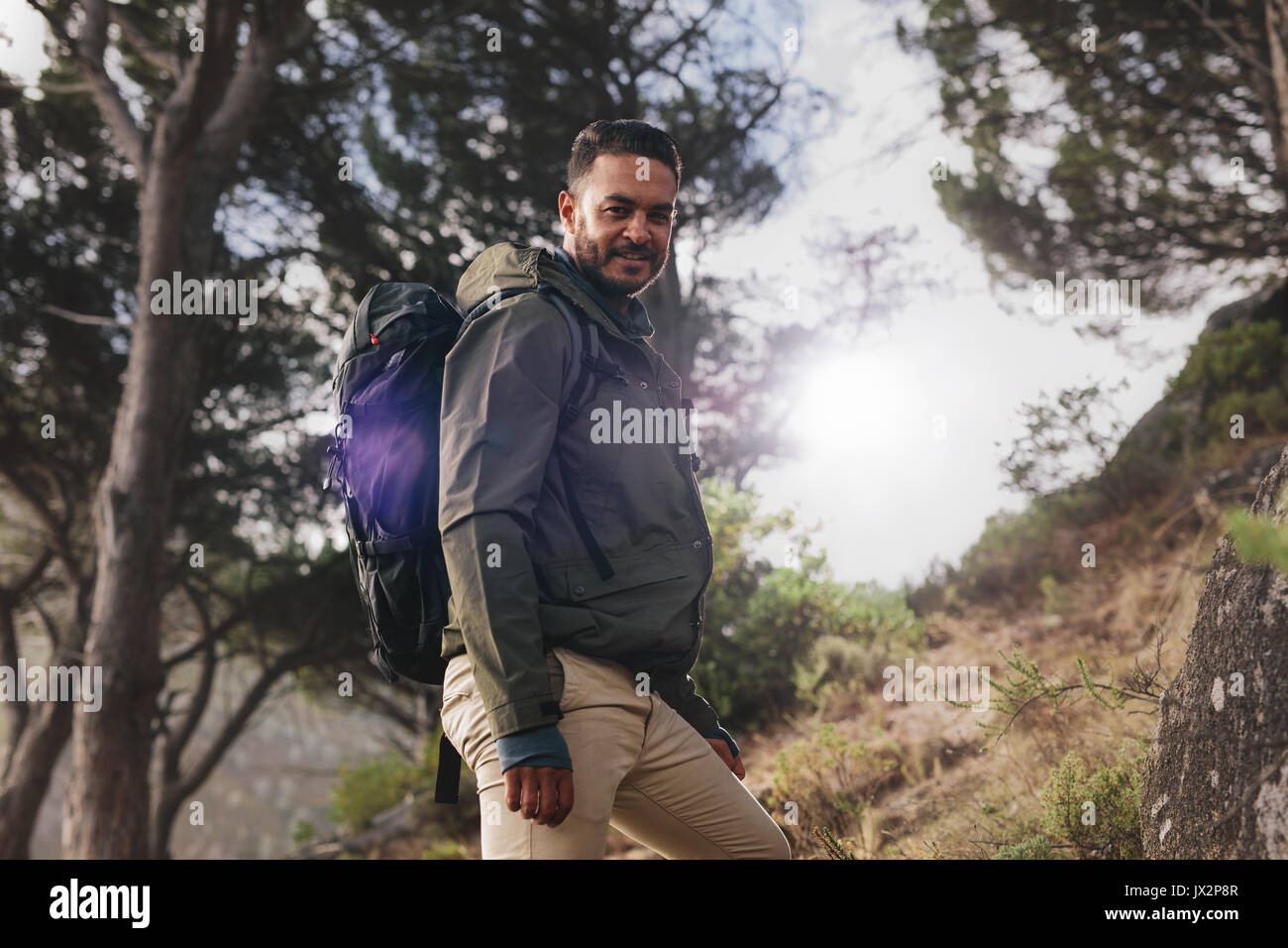 Portrait of handsome young man with backpack on mountain trail ...