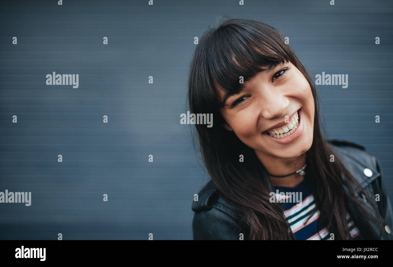 Close up portrait of beautiful female model smiling against gray ...