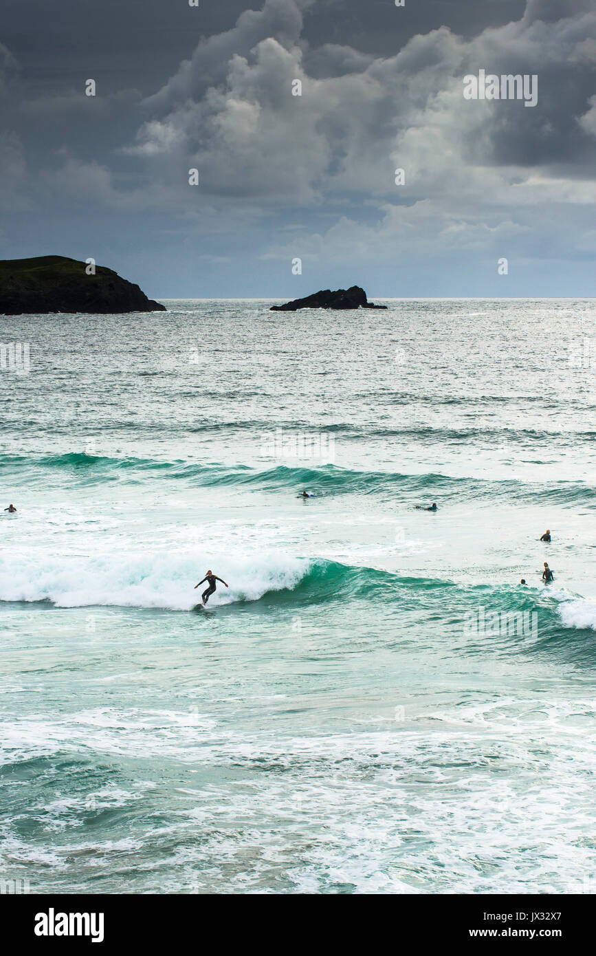 Surfing UK. A surfer riding a wave at Fistral as dark clouds gather ...