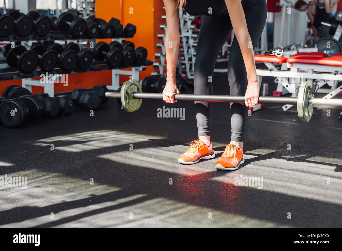 Woman doing shoulder press exercise with a weight bar inside a gym ...
