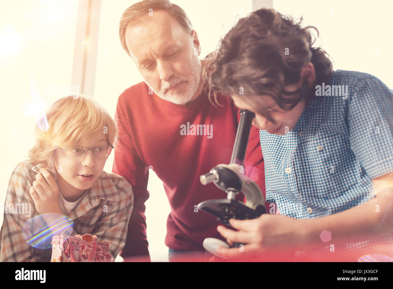 Attentive boy with curly hair looking through eyepiece Stock Photo - Alamy