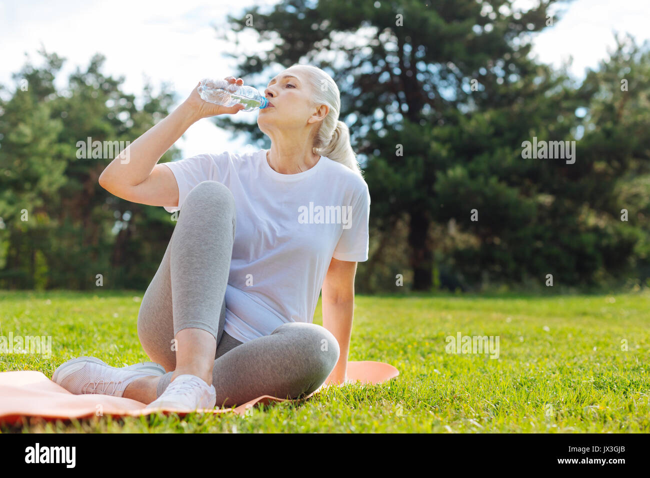 Exhausted elderly woman drinking water Stock Photo - Alamy