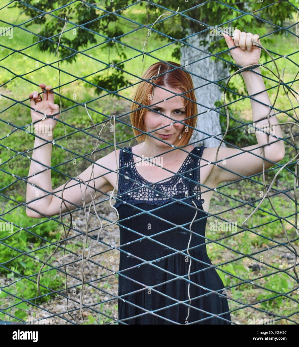 Girl posing behind an old iron gate. Since the fence is only gate ...