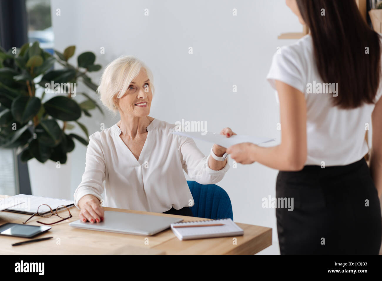 Nice pleasant woman giving her secretary a document Stock Photo - Alamy