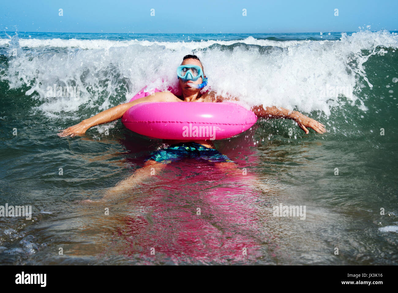 a young caucasian man wearing a diving mask, a snorkel and a pink swim ...