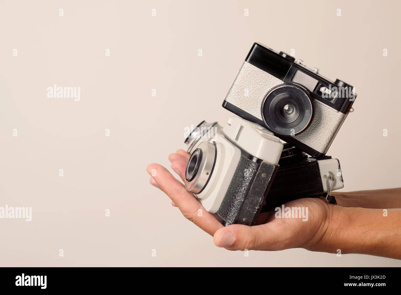 closeup of a young man with a pile of old film cameras in his hands ...