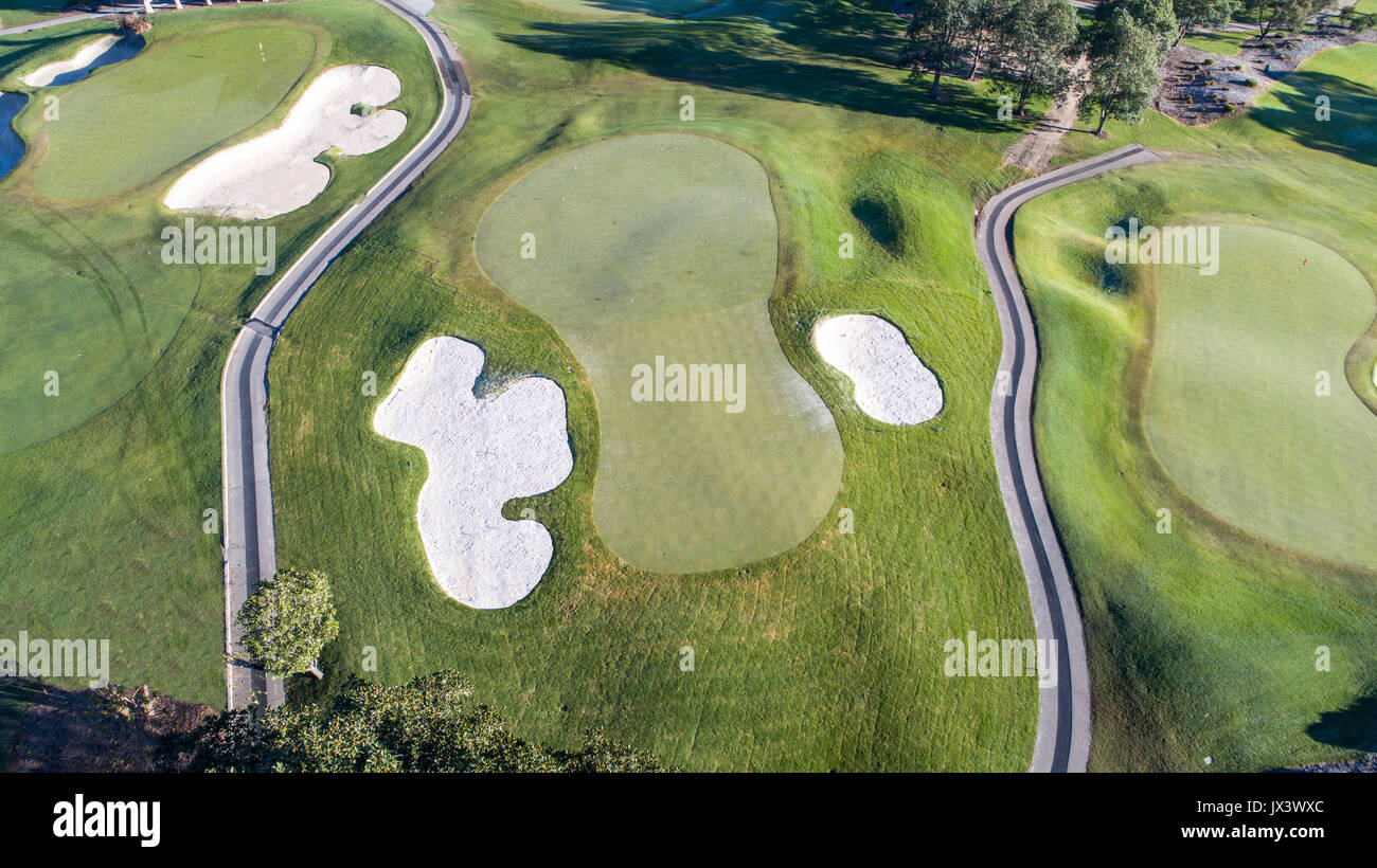 Aerial view of golf course green with flag, bunkers and golf cart ...