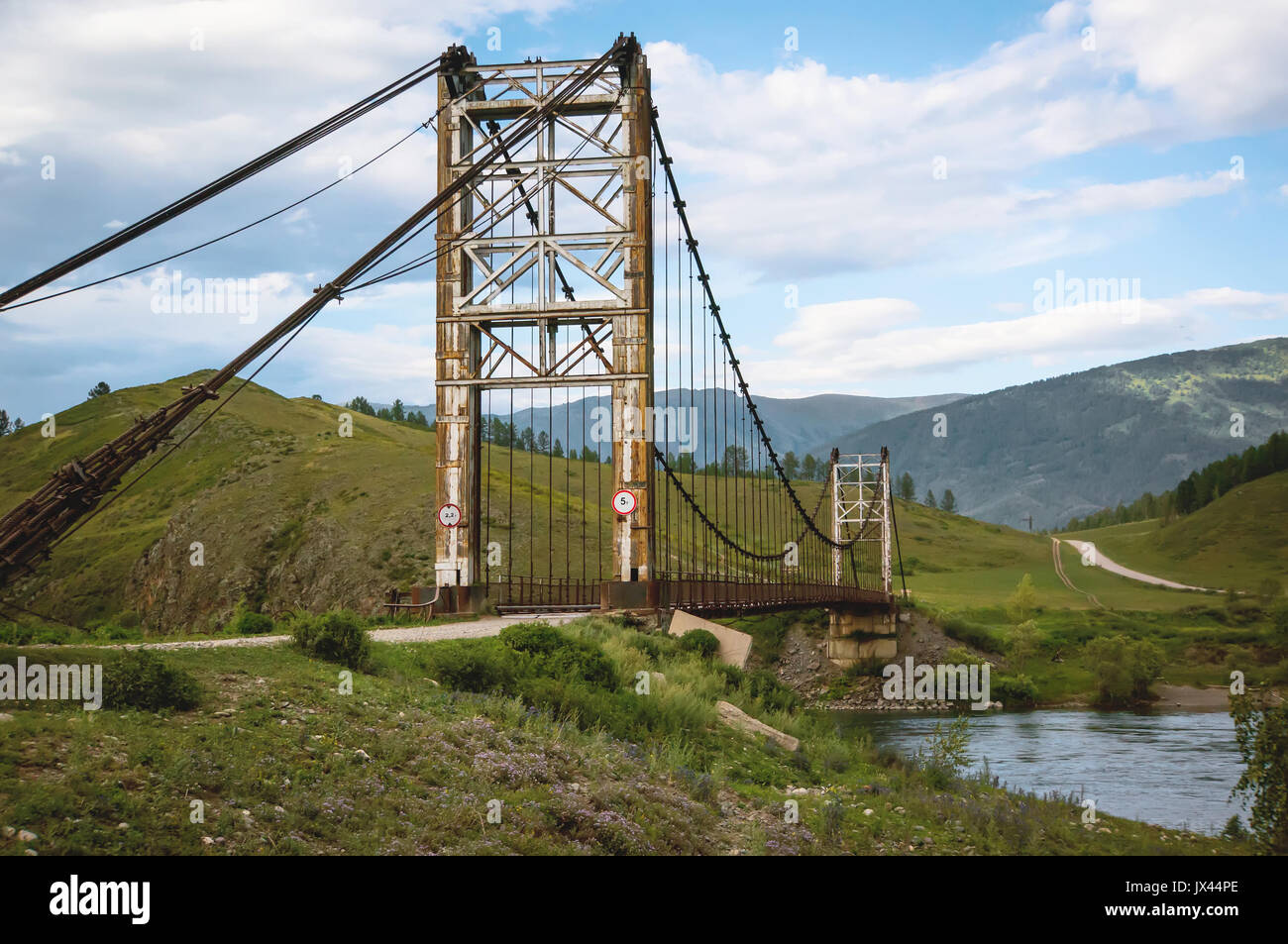 wooden suspension bridge over a mountain river high in the mountains of ...