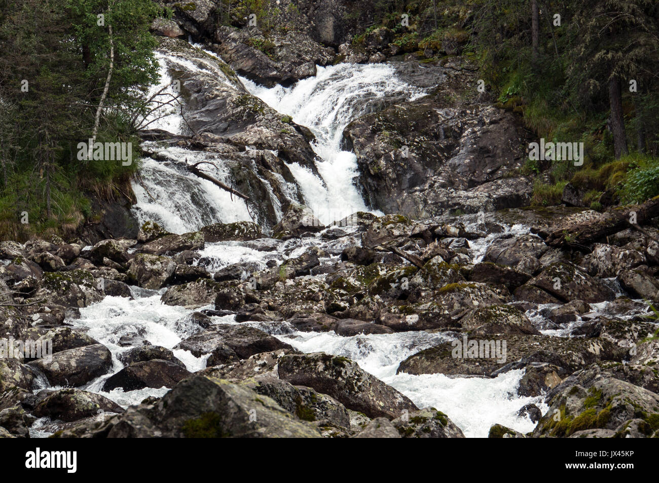 Water flowing through rocks. A small waterfall in the mountains in the ...